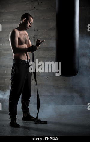 Male boxer in boxing bandages trains and hits punching bag. Athletic ...