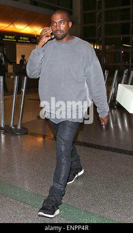 Kanye West talks on his cell phone as he departs from Los Angeles ...