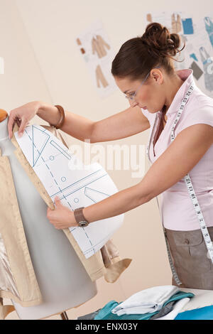 Female dressmaker cutting fabric into pattern pieces in workshop Stock ...