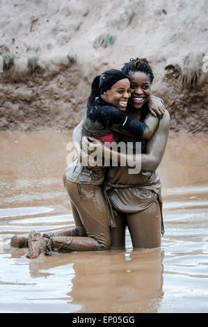 Mud covered young woman competitor waist deep in mud lake, obstacle course race Stock Photo - Alamy