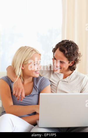 Two cute women working using laptop in living room on sofa. Friends ...