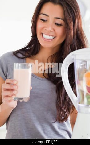 Beautiful woman using a blender while holding a drink Stock Photo - Alamy
