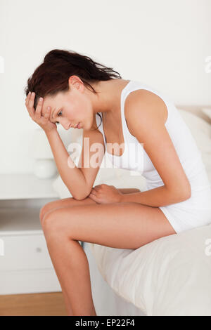 Young woman with bad cold lying in bed under blanket and using nasal ...