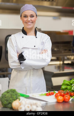 Smiling chef folding her arms beside vegetables Stock Photo - Alamy