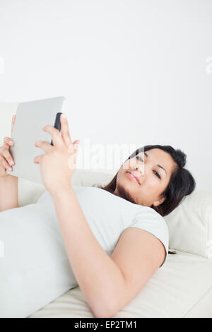 Woman looking at a tactile tablet while holding a card in a living room ...