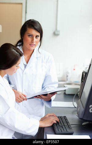 Cute scientist typing a report with her computer Stock Photo - Alamy