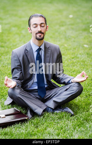 Young businessman meditating in the garden Stock Photo - Alamy