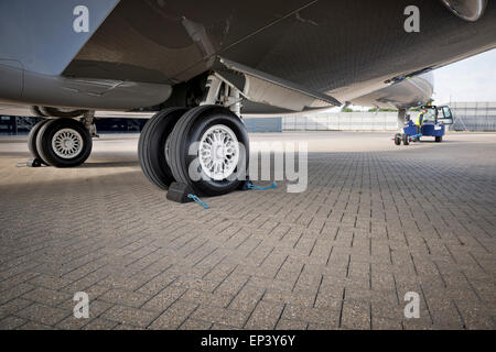 A landing wheel of an airplane with chocks. The plane is stationery ...