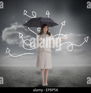 Businesswoman with jumbled arrows holding umbrella and smiling in dark ...