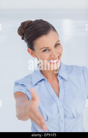 Woman extending hand to camera with a smile in an outdoor street ...