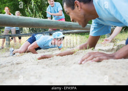 Fit people crawling under the net during obstacle course in bootcamp ...