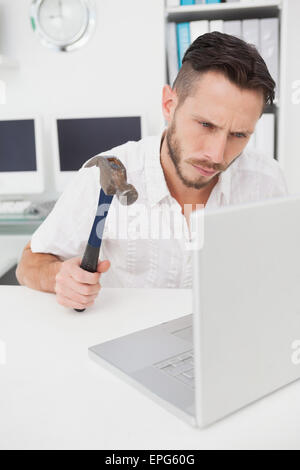 Casual businessman holding hammer over laptop Stock Photo - Alamy