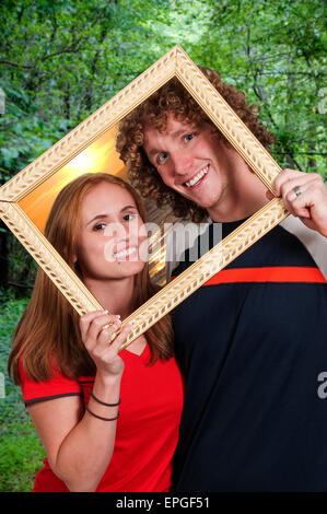 Happy couple in frame. Beautiful young couple looking through a picture ...