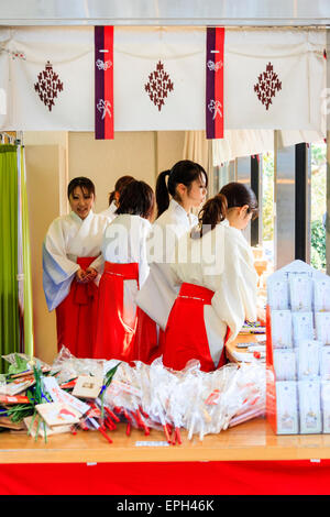 A shrine maiden in red and white robes in a courtyard at the ...