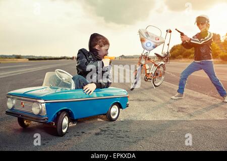 Two boys playing cops and robbers Stock Photo - Alamy