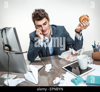 Slacker man talking on the phone while eating at work / modern office ...