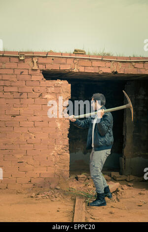 Guy knocking down a wall using a pickaxe Stock Photo - Alamy