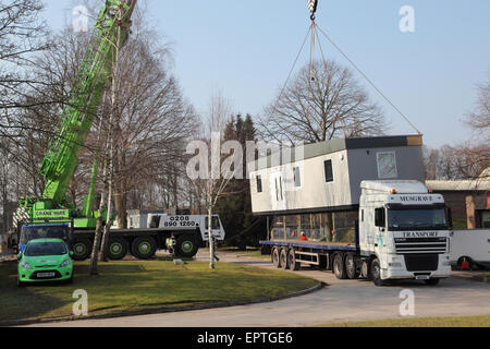 A section of a modular classroom building is lifted from an articulated ...
