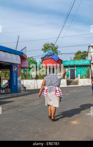 A person carrying items in a village street with rustic, earthen ...