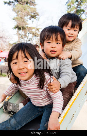 Japanese children, 7-9 year old. Three happy girls in a row, leaning ...
