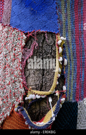 Colourful knitted and crocheted yarns wrap a trunk of a "Yarn Bombed ...