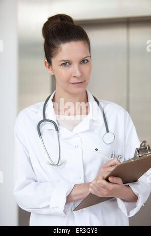doctor writing on a medical chart with fake patient in hospital room ...