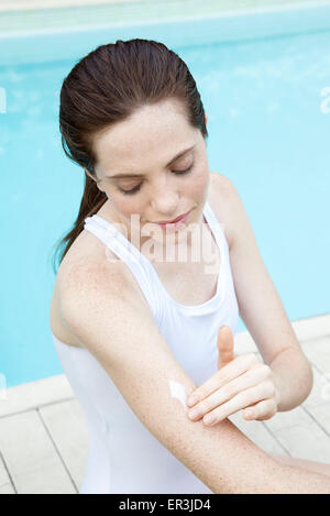 Cropped view of woman applying sunscreen on back of smiling friend ...