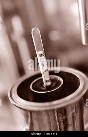 Alcoholmeter floating in alcohol at craft distillery. Vertical B/W ...