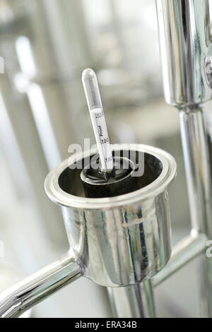 Alcoholmeter floating in alcohol at craft distillery. Vertical B/W ...