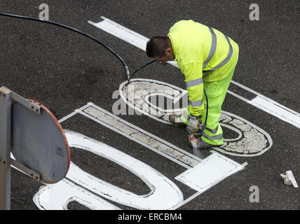 Workman repainting Stop sign on road Stock Photo - Alamy