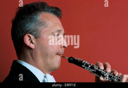 Man playing oboe against red background. Close-up. Side view Stock ...