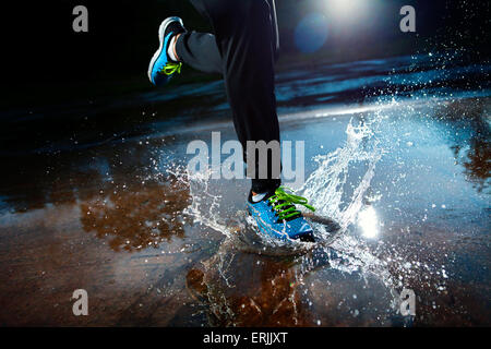 Single runner running in rain and making splash in puddle Stock Photo ...