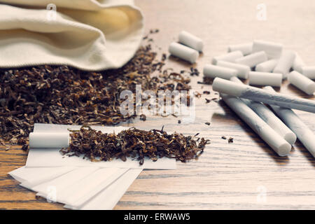 Rolling cigarettes with filters papers and plenty finely cut tobacco ...