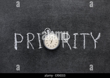 priority word handwritten on chalkboard with vintage precise stopwatch ...