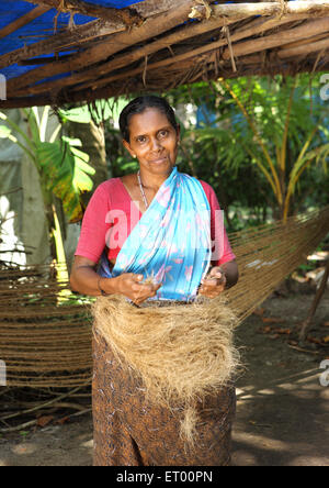 Keralite woman making coir rope in cottage ; traditional method ...