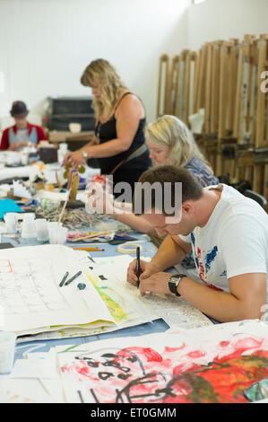 Four creative students of art school feeling joyful while painting ...