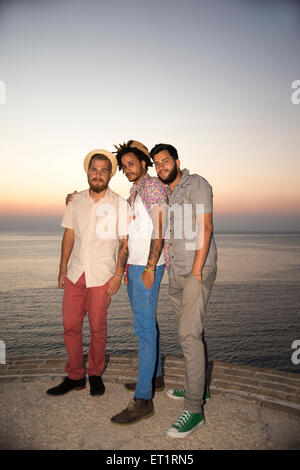 Three friends watching a sunset Stock Photo - Alamy
