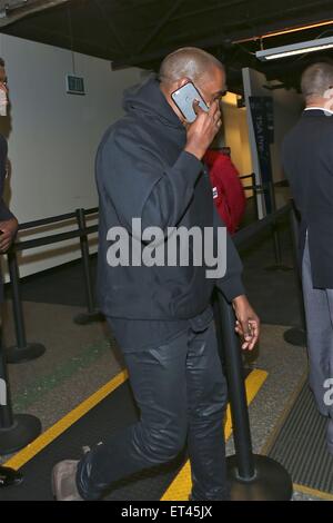 Kanye West talking on his cellphone as he leaves on a flight from Los ...