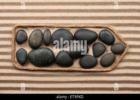 Pointer made of rope with black stones, lying on the sand Stock Photo ...