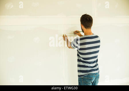 Young man renovating drawing marking at wall Stock Photo - Alamy
