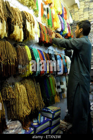 Peshawar, Pakistan. 16th June, 2015. A man tries on a traditional cap ...