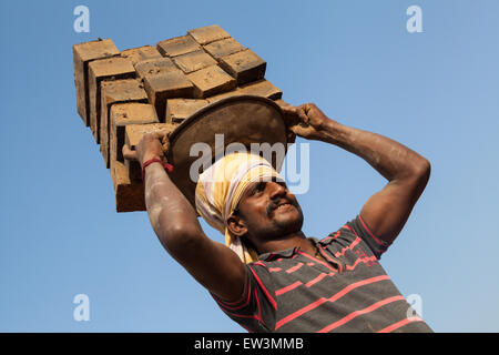 Male worker carrying bricks on his head at a brick factory in Harihar ...