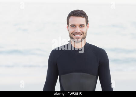Man in wetsuit smiling on sunny beach near modern buildings Stock Photo ...