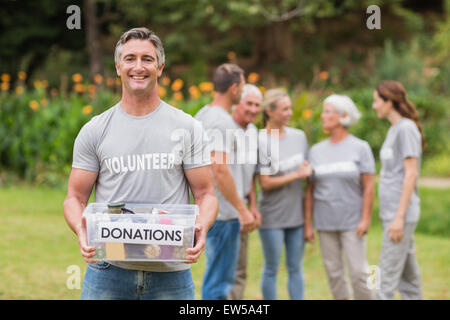 Senior man volunteer holding donations box putting food into a box ...