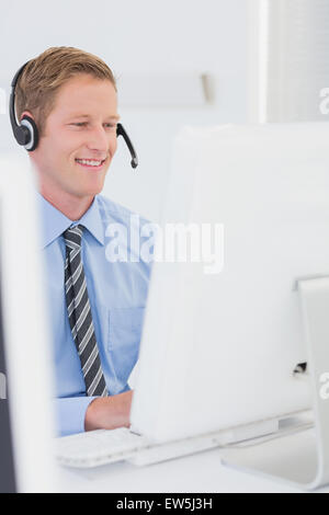 Handsome agent with headset typing on keyboard Stock Photo - Alamy