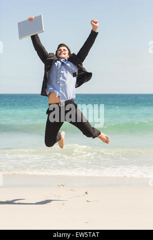 Young businessman jumping with laptop Stock Photo - Alamy