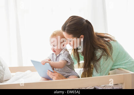 Mother and baby boy using tablet computer while sitting on bed Stock ...