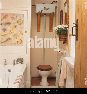 Wooden cistern above toilet in cottage bathroom with wooden swing doors ...