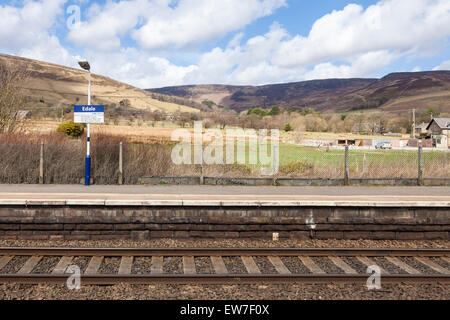 A sign at Edale railway station, with the Kinder Scout plateau behind ...