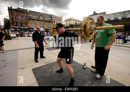Man competing in a strongman contest lifts a very heavy Atlas Stone ...